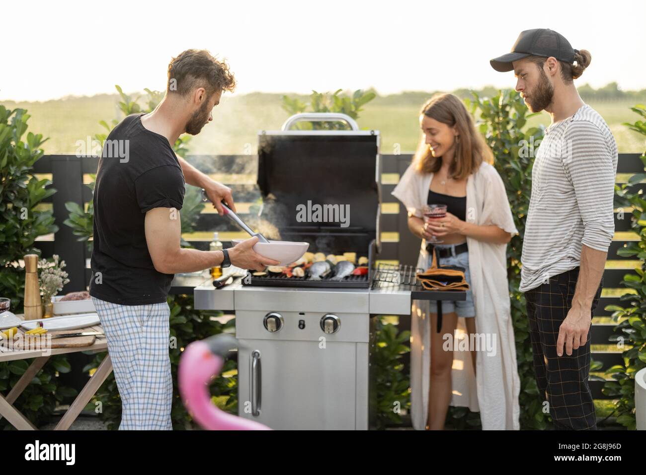 Young friends grilling at backyard Stock Photo - Alamy