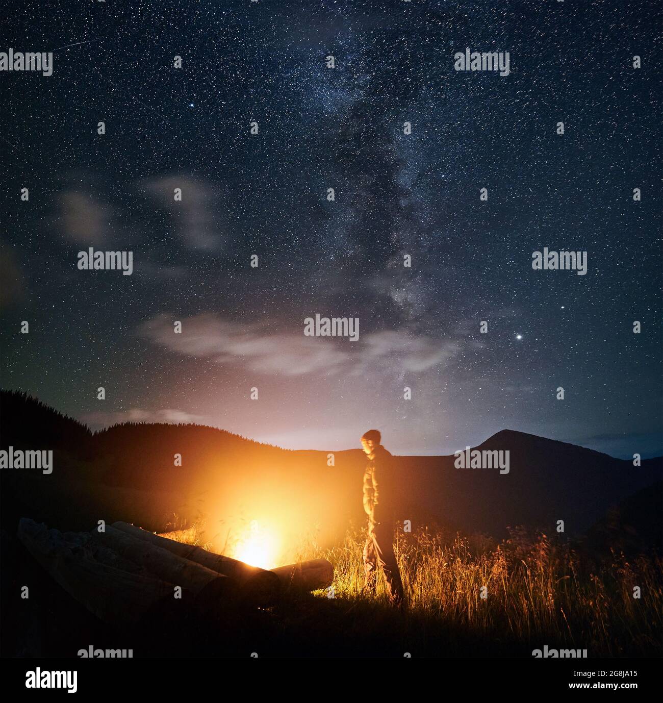 Side view of man standing and enjoying near fire and relaxing under ...