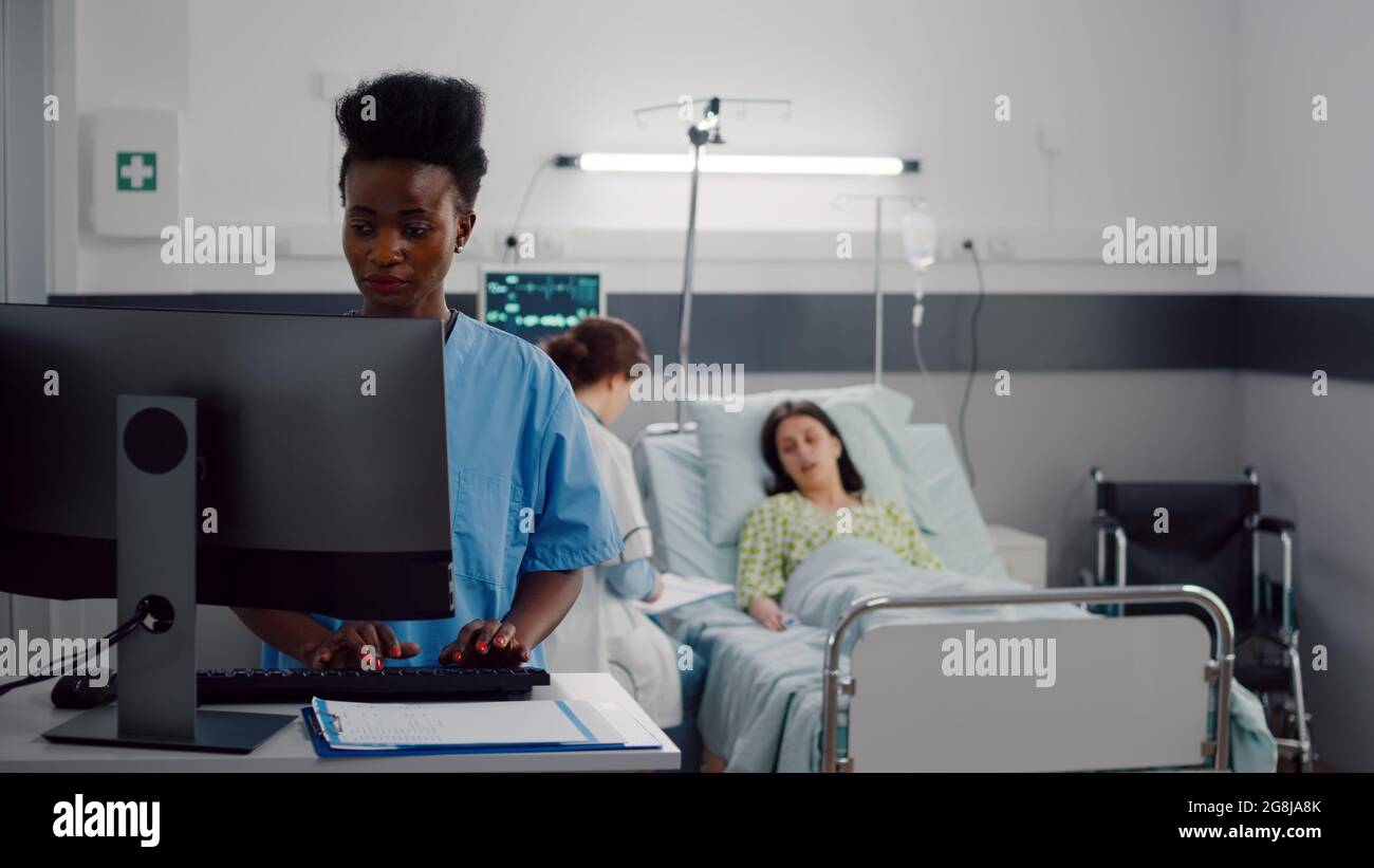 Black assistant typing healdcare treatment on computer while in ...