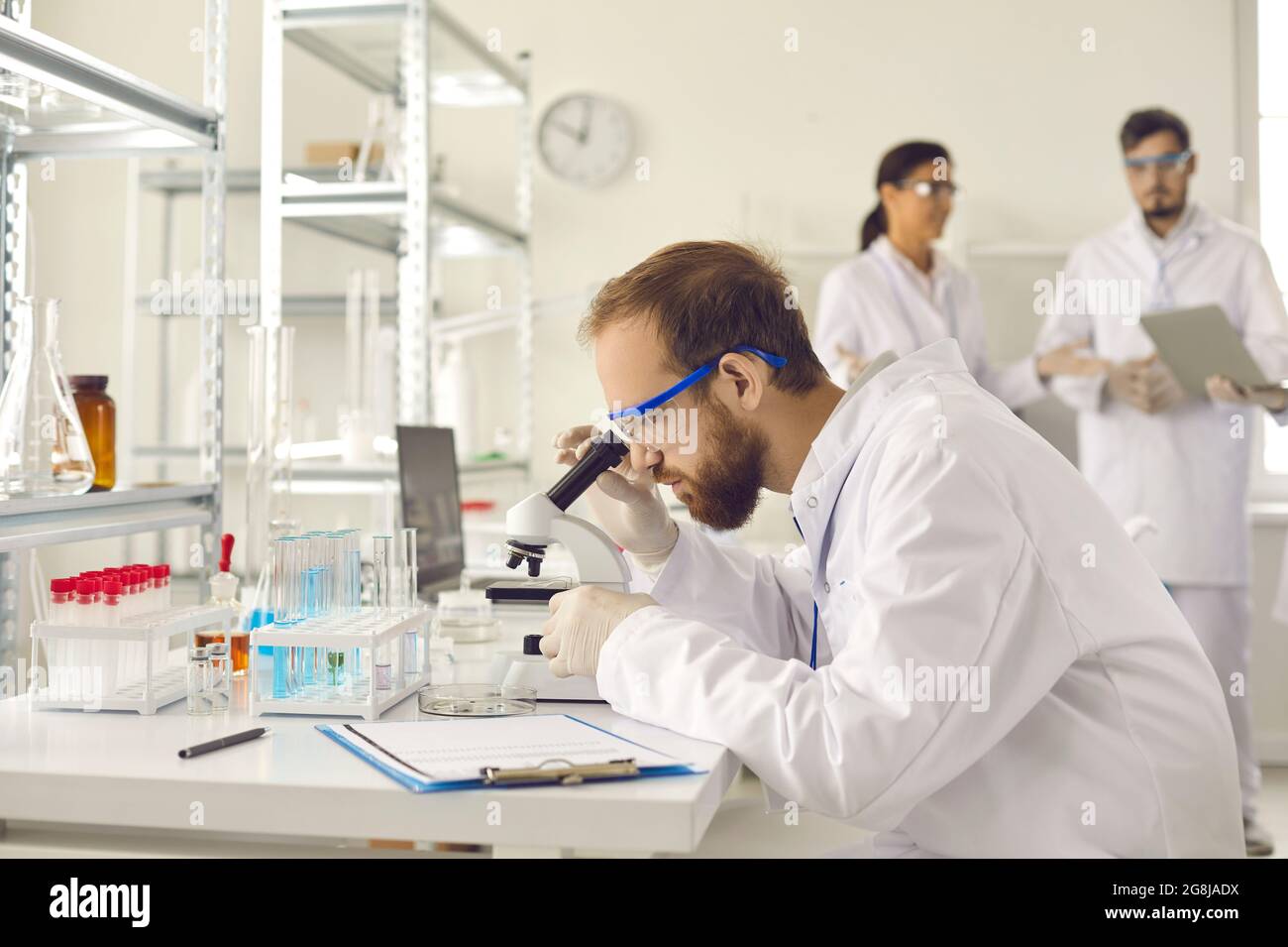 Professional male scientist looking through microscope in research ...