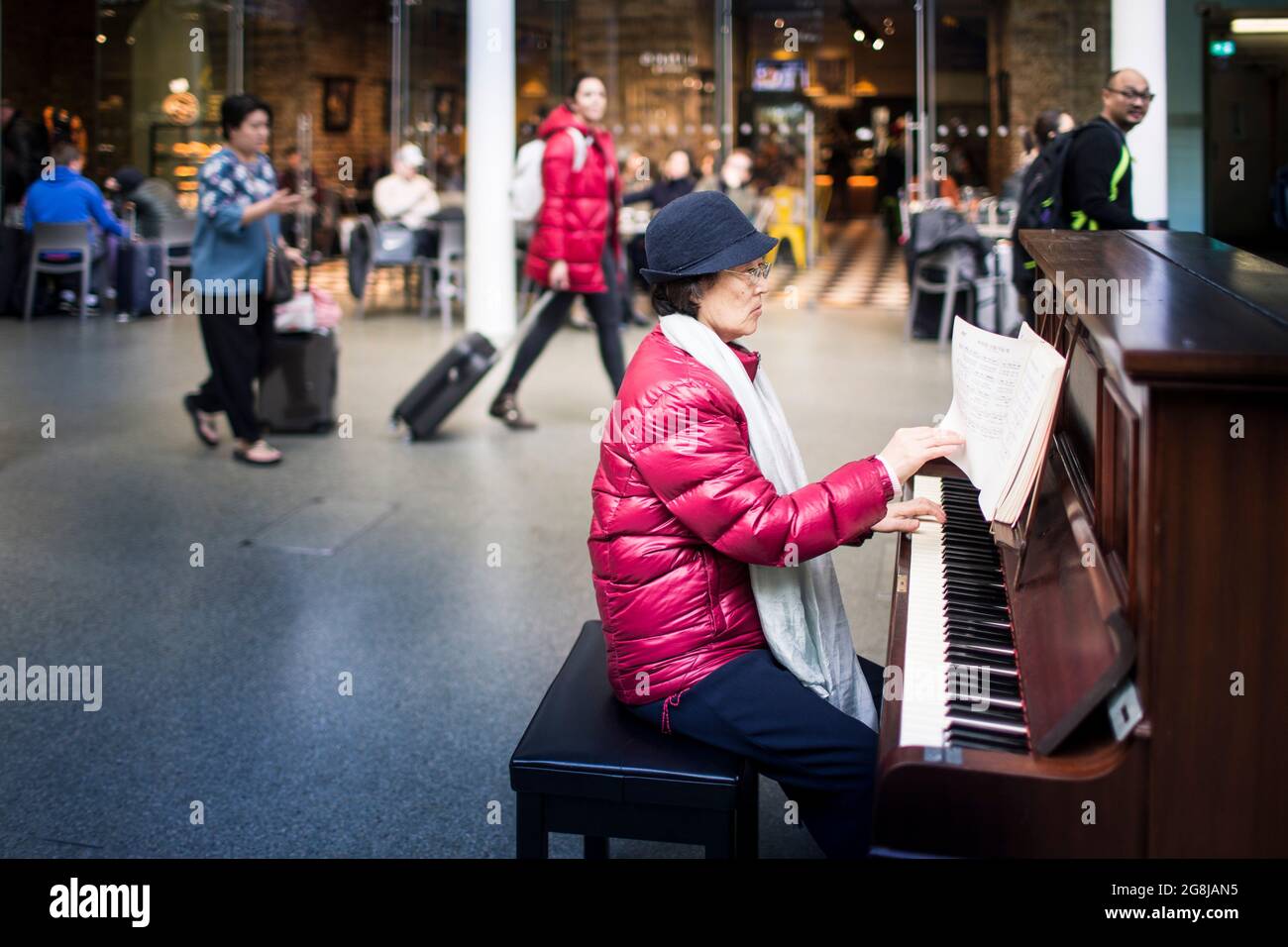 A Japanese lady plays piano in the concourse at Kings Cross St Pancras ...