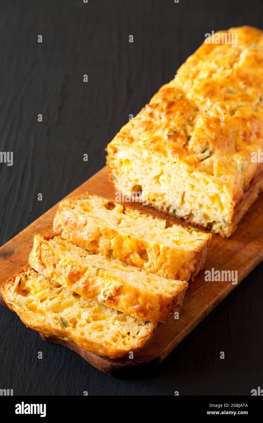 Homemade Cheesy Bread Loaf on a rustic wooden board on a black surface ...