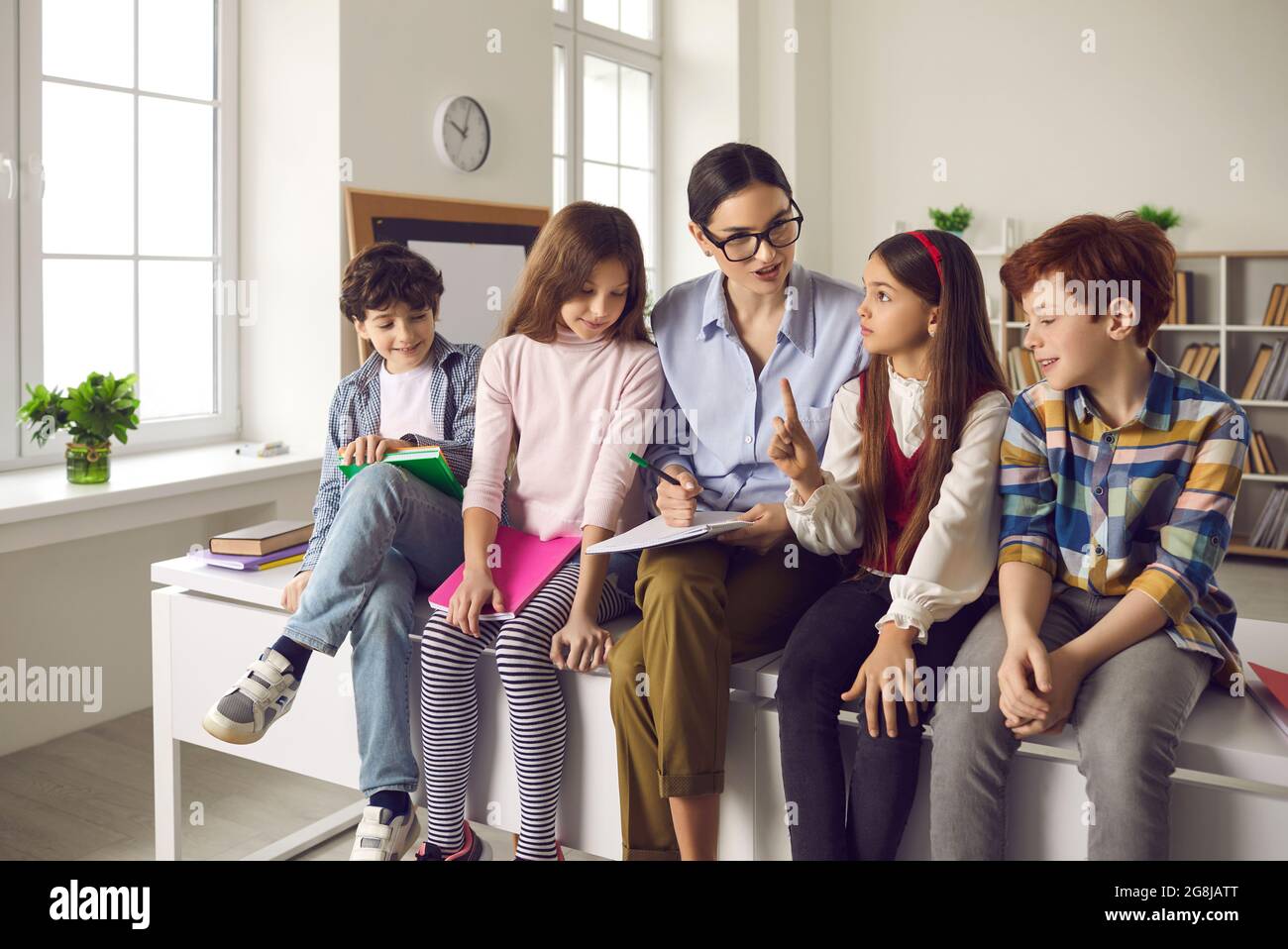 Young female teacher and a small group of children communicate and ...