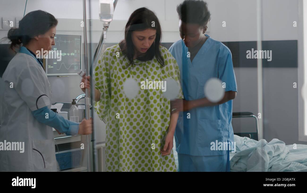 Black asisstant with practitioner doctor helping patient to stand up ...