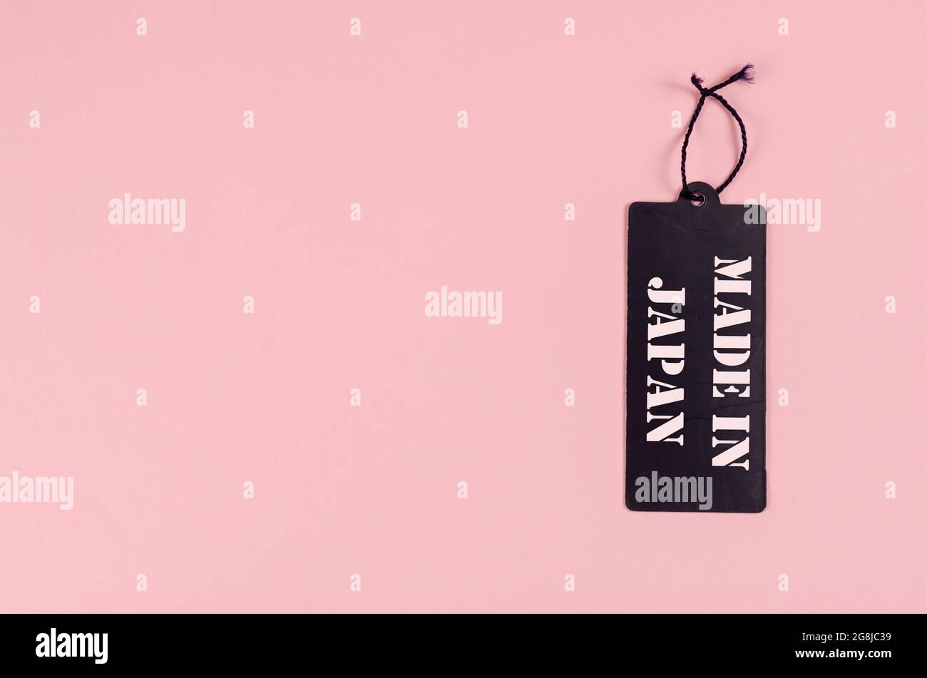 Made in Japan. Black tag on pink background. Paper rectangular tag with ...