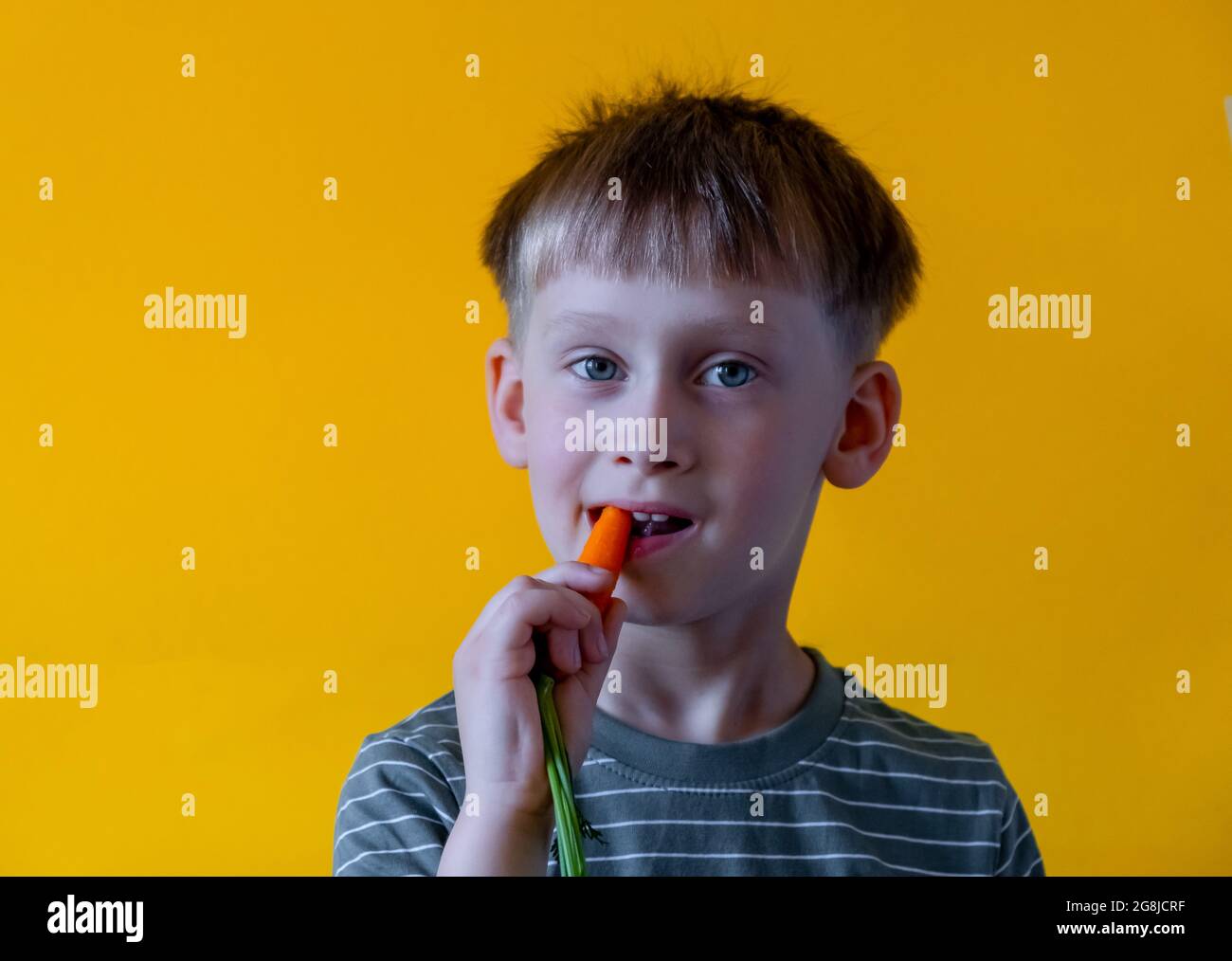 Boy eating fresh carrots on an orange background Stock Photo - Alamy
