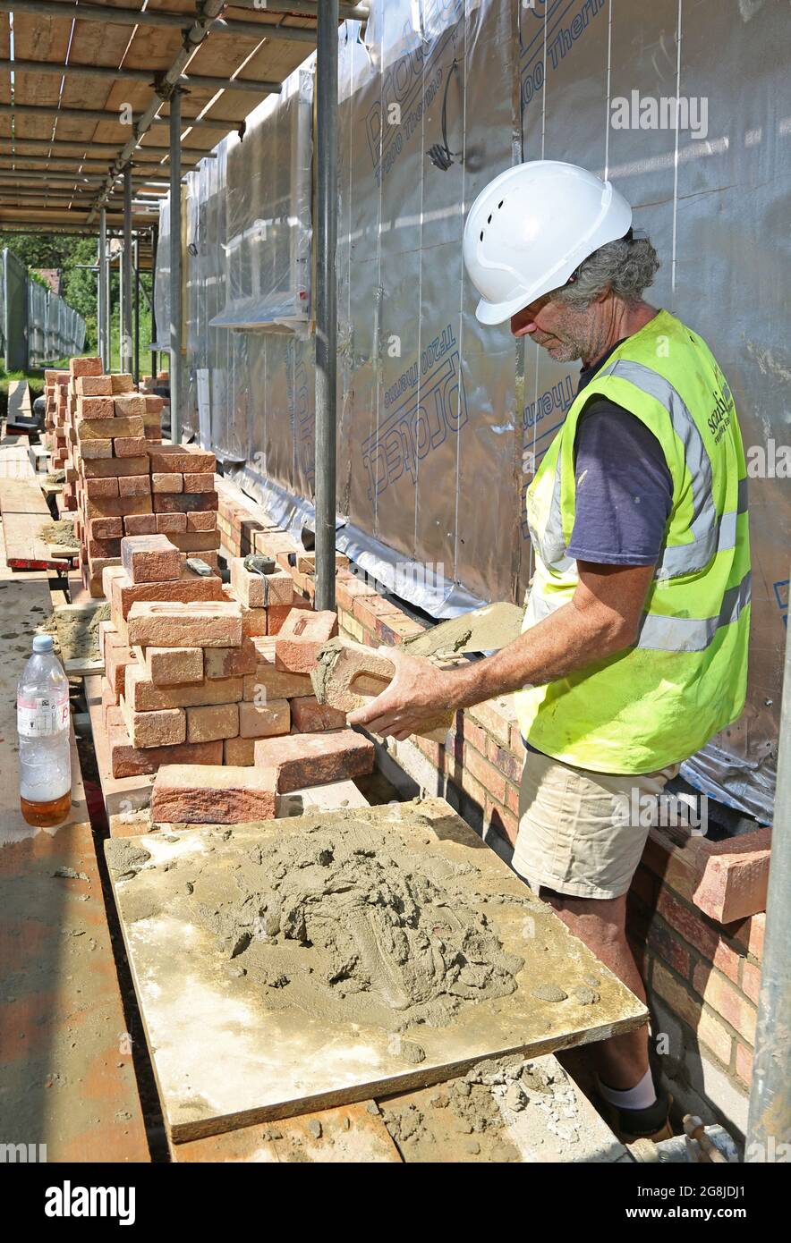 A brick layer constructs the external wall of a new bungalow in Surrey ...