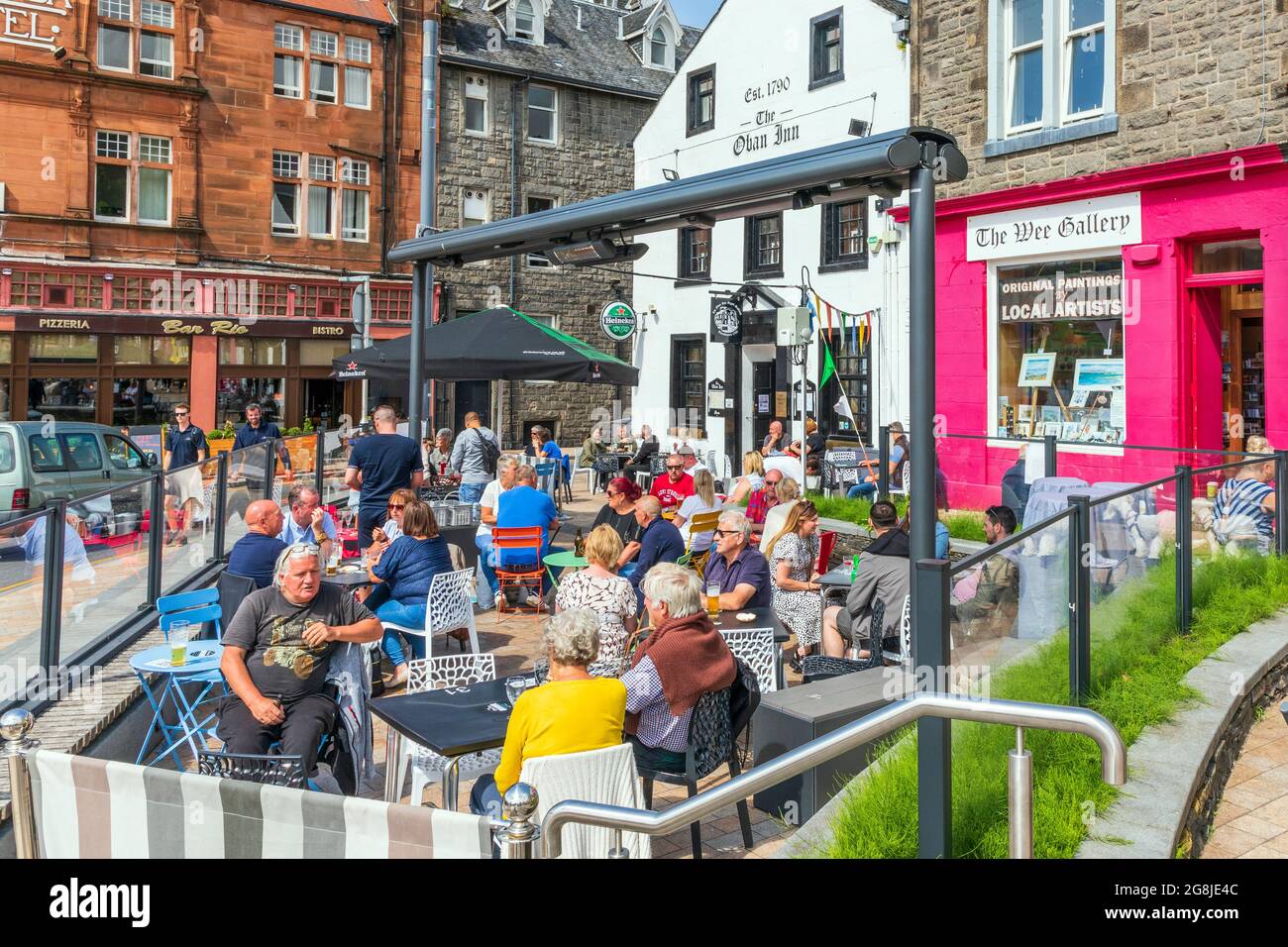 Tourists and patrons eating and drinking outdoors at the Oban Inn ...