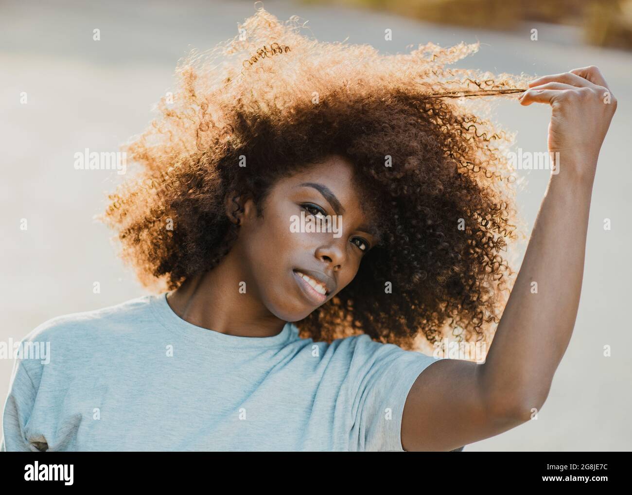 Black woman touching curly hair Stock Photo - Alamy