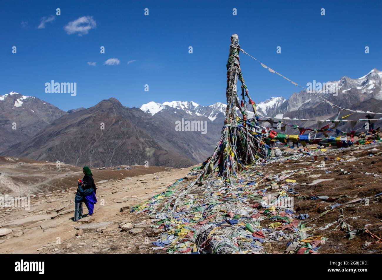 Woman and child near A ritual site with colorful flags in the Indian ...