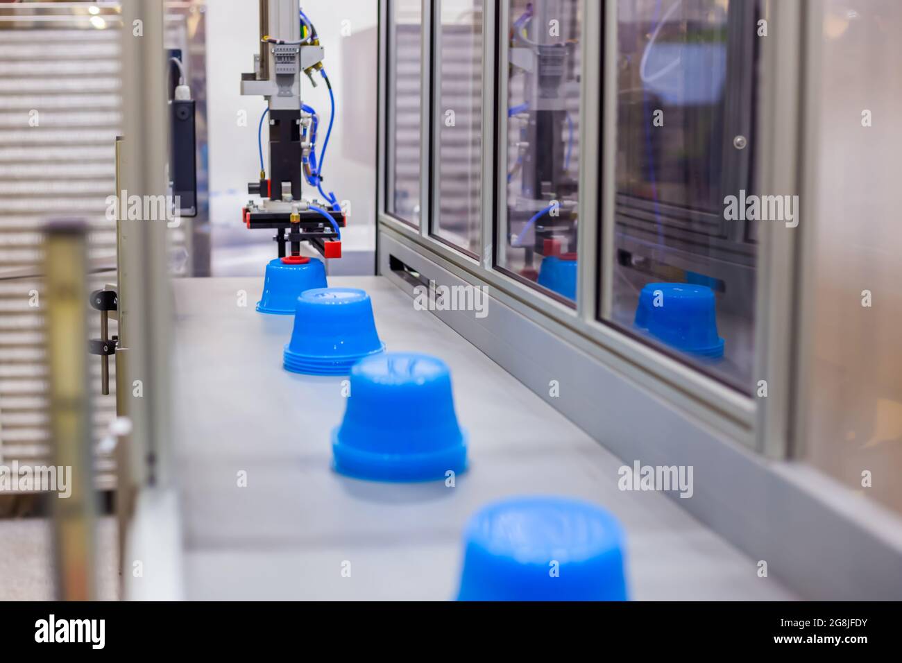 Blue pots on conveyor belt of plastic injection molding machine with ...