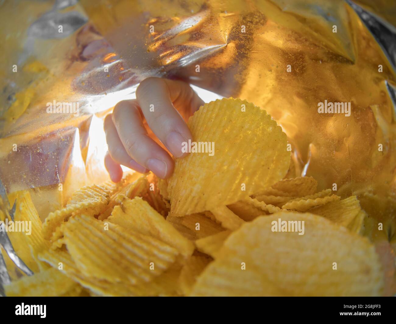 Hand taking potato chips inside the bag Stock Photo - Alamy
