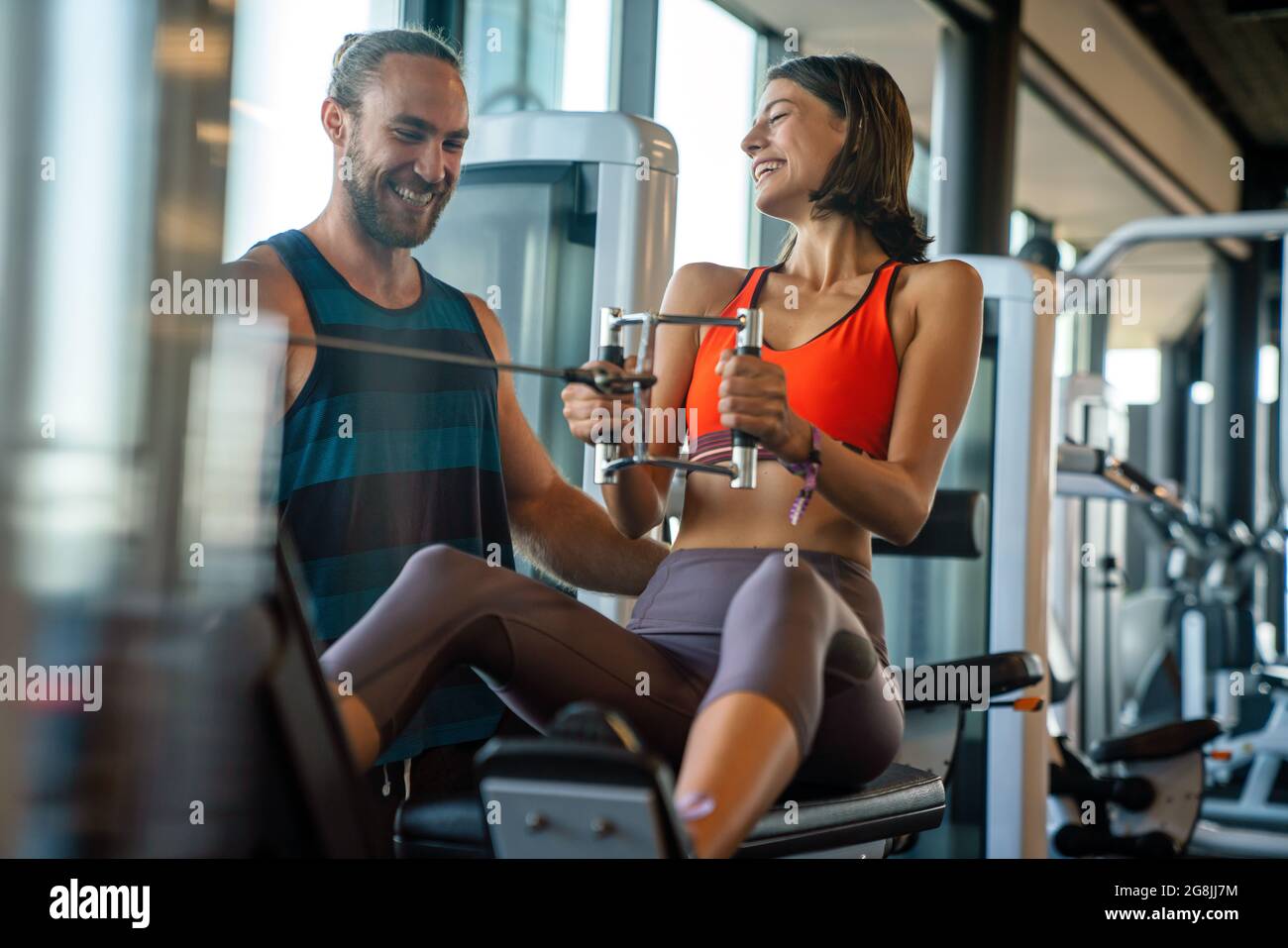 Personal trainer helping woman working out in gym Stock Photo - Alamy