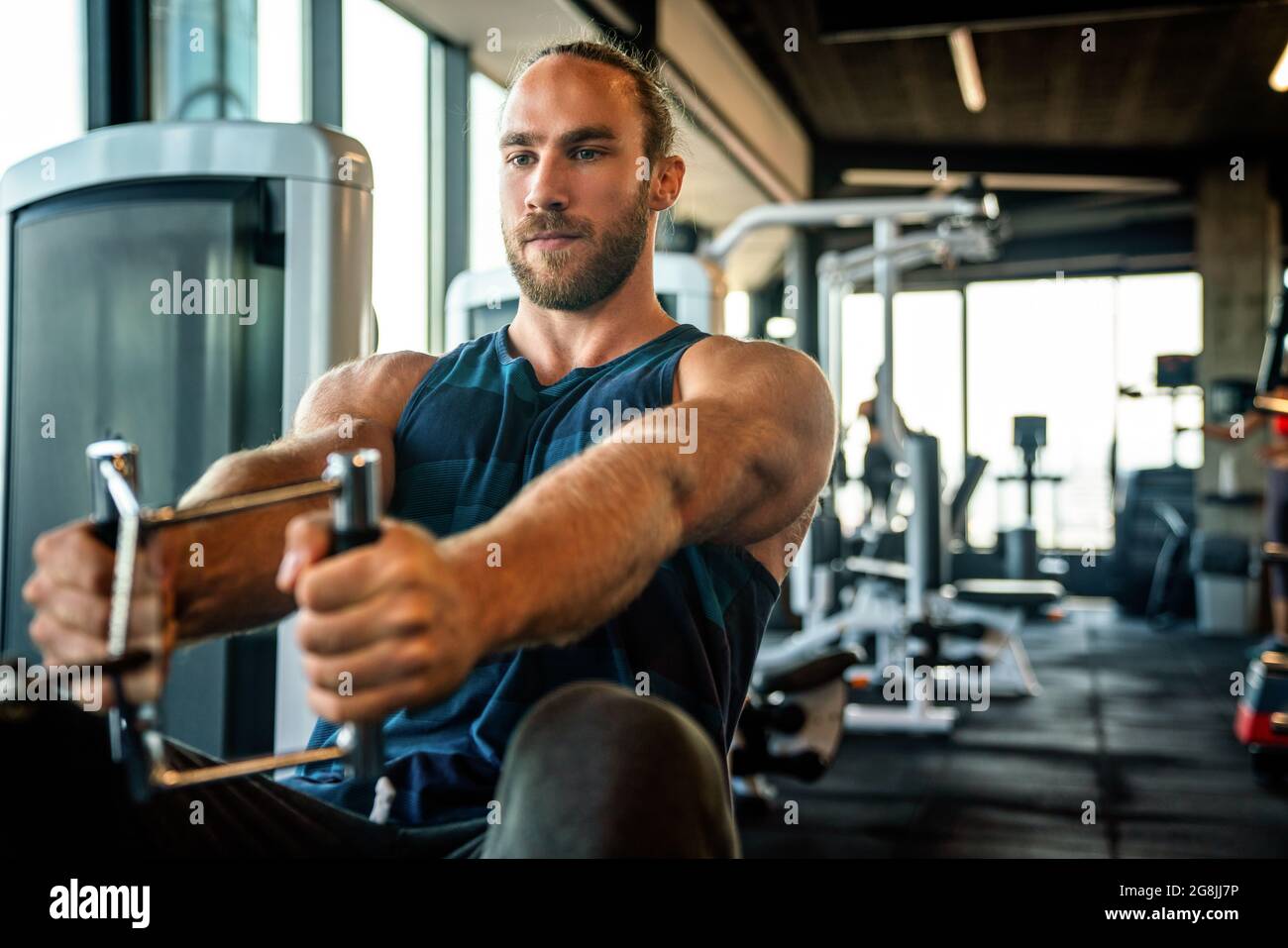 Fit man exercising at the gym on a machine Stock Photo - Alamy