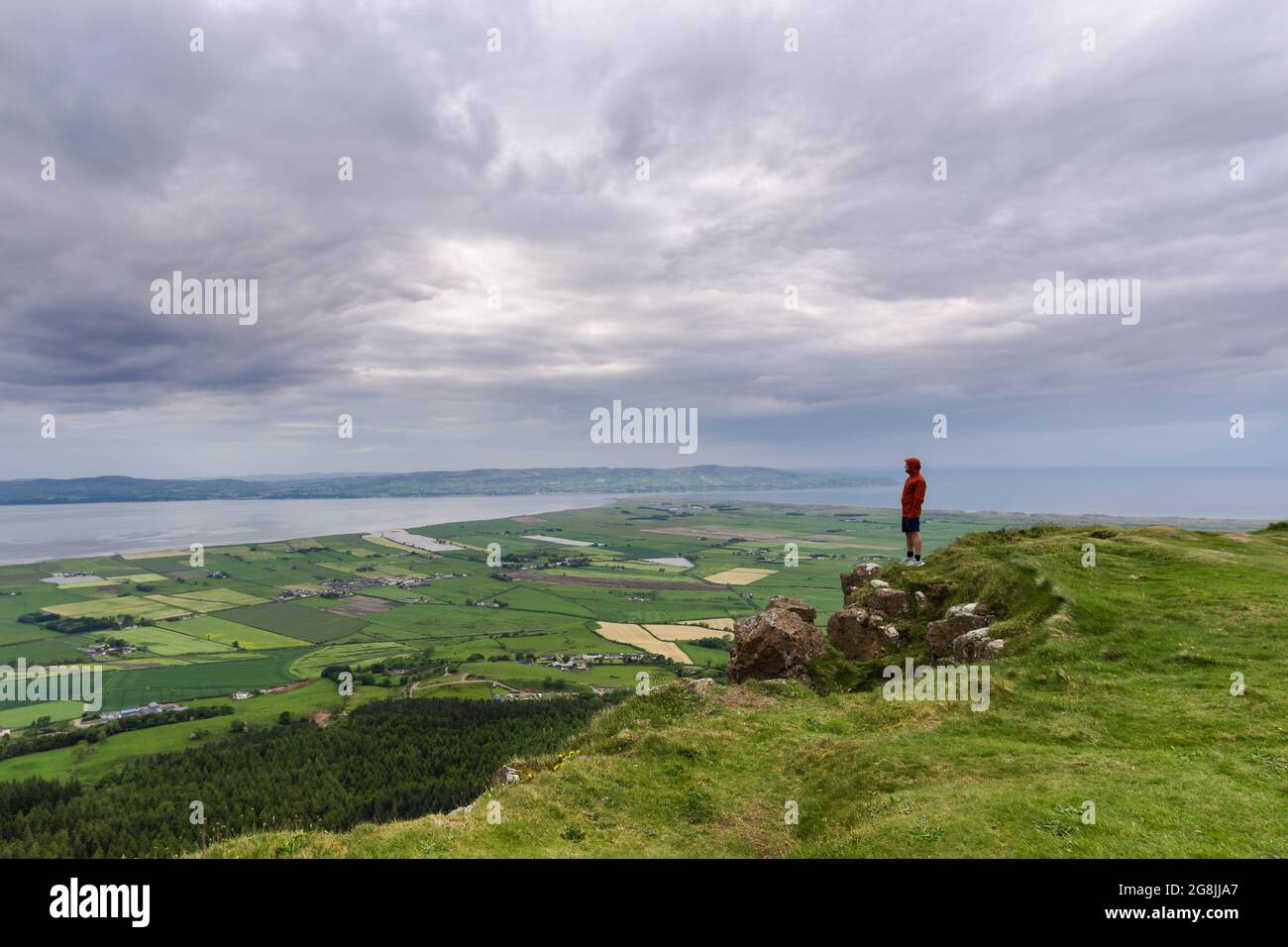 Caucasian male with a red jacket standing on the rocks with a beautiful ...