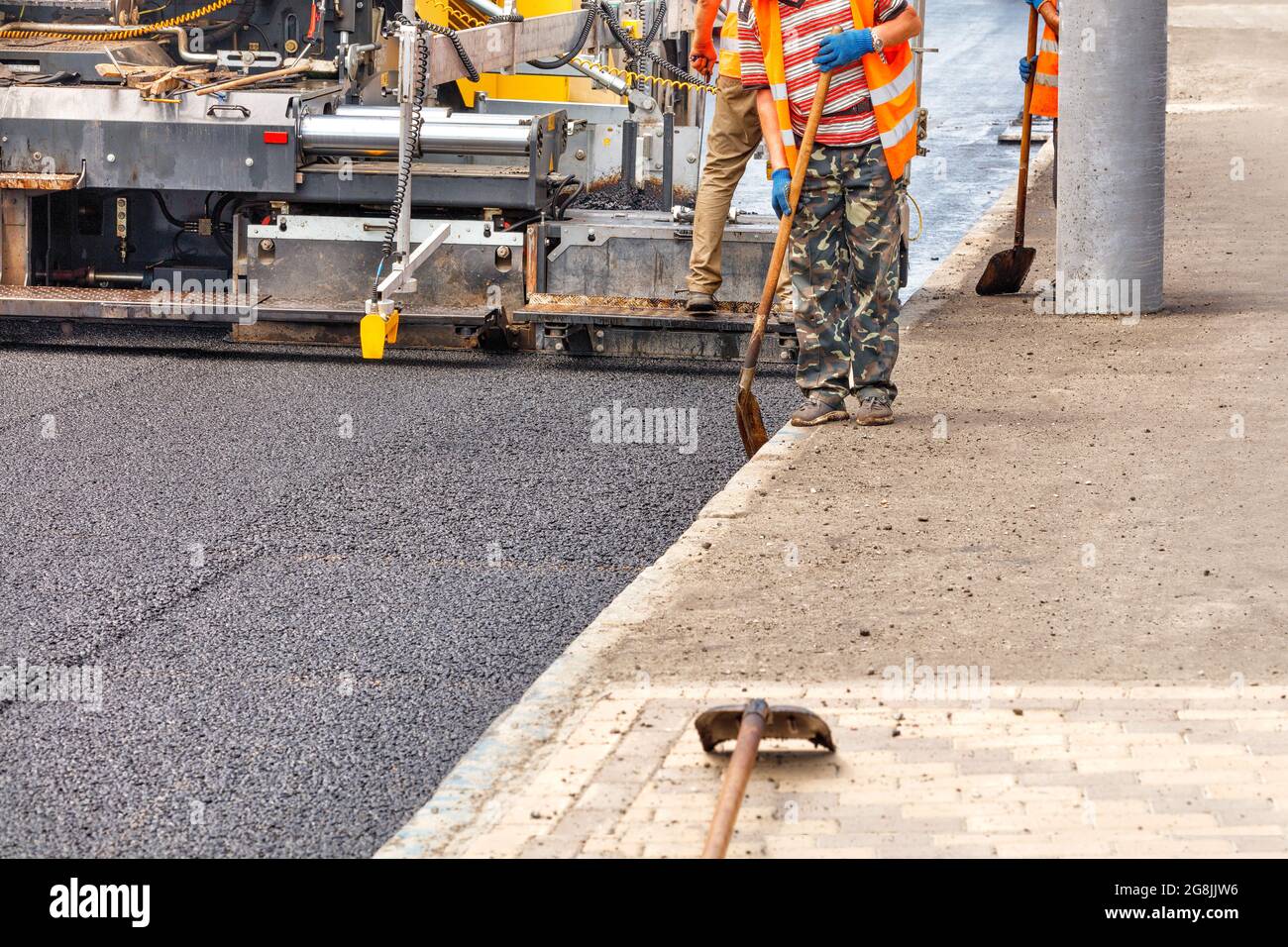 An industrial paver is laying a layer of new hot asphalt on the ...
