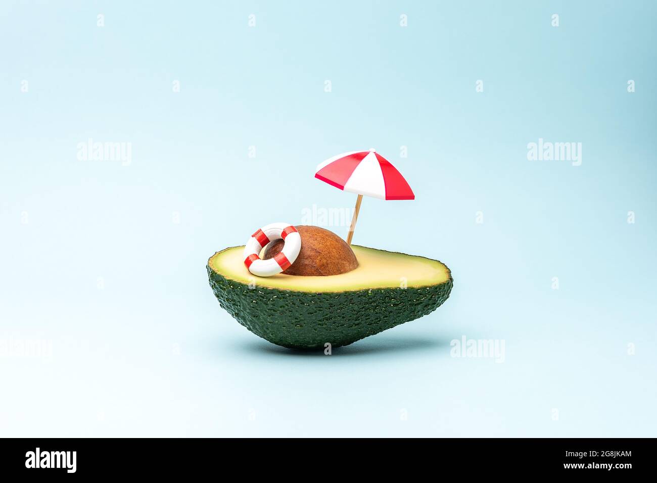 Summer beach concept made with avocado fruit, sun umbrella and swimming ...