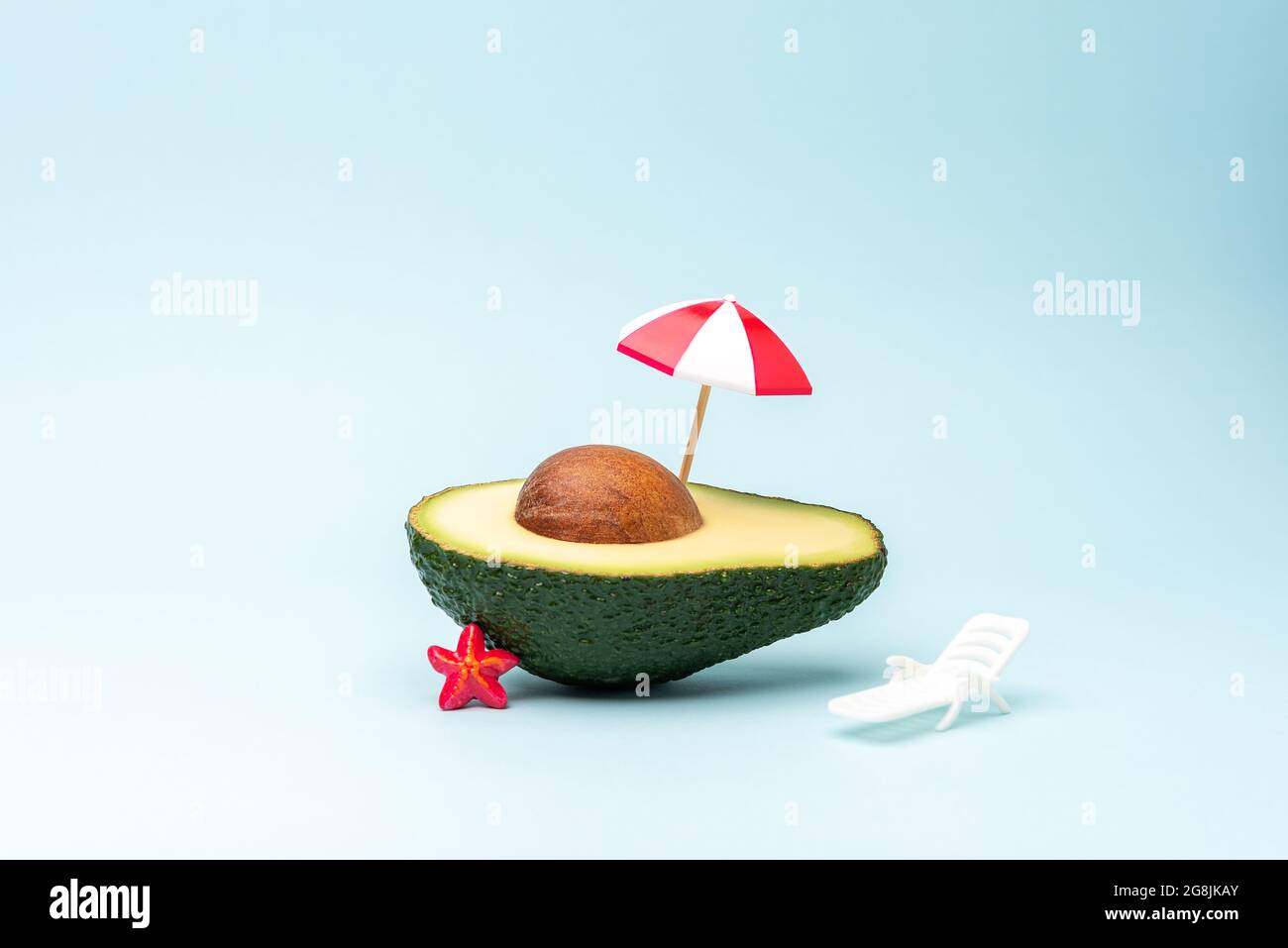 Summer beach background made with avocado fruit, sun umbrella and ...