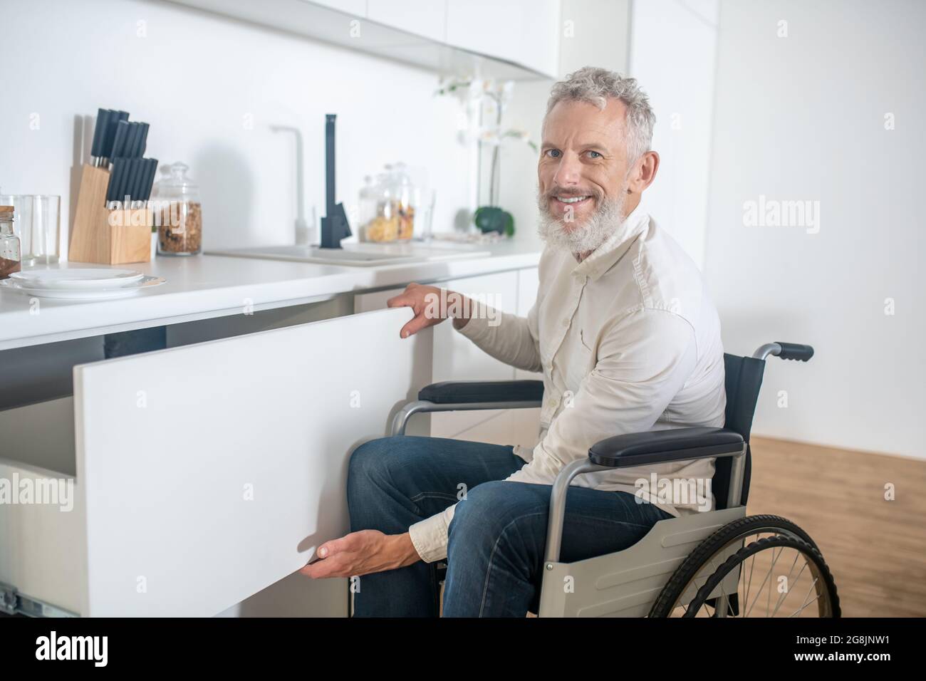 Gray-haired handicapped man in the kitchen smiling nicely Stock Photo ...