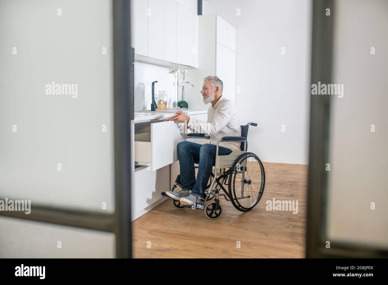 Gray-haired handicapped man in the kitchen getting the breakfast ready ...