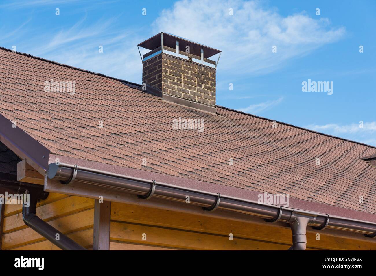 Bitumen asphalt roofing shingles and brick chimney pipe on a wooden ...