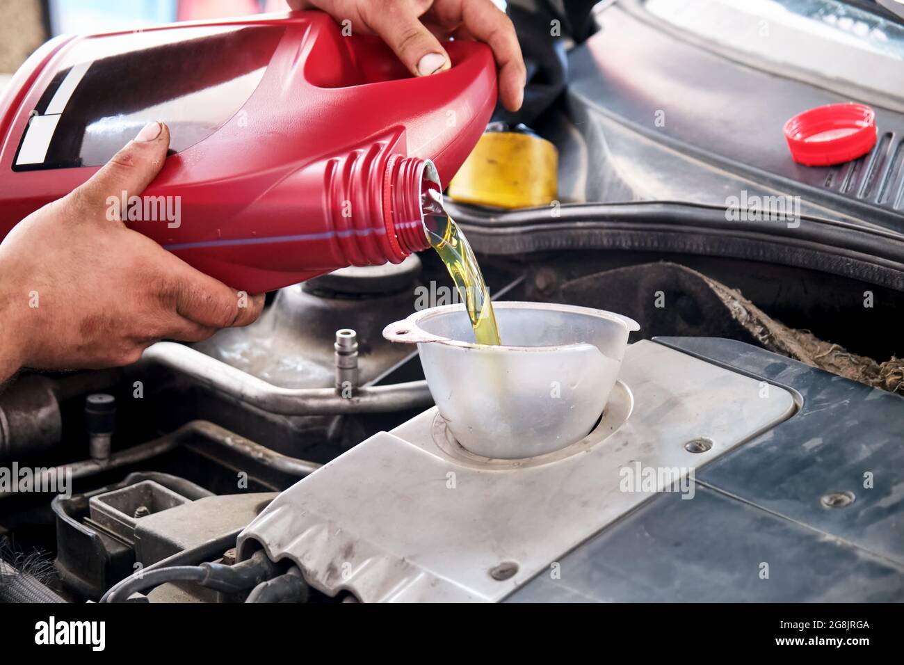 Hands of a mechanic repairman adding or pouring oil to the car engine ...