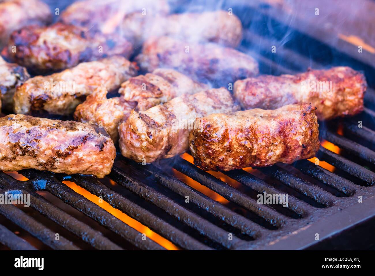 Closeup of meat rolls called mici or mititei on a brazier with burning ...