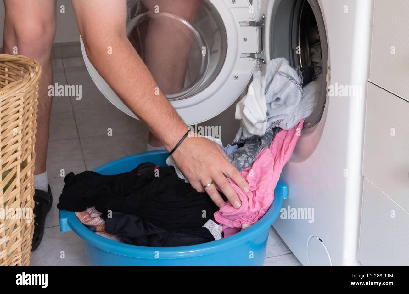 Close-up shot of woman hand loading dirty clothes in washing machine ...