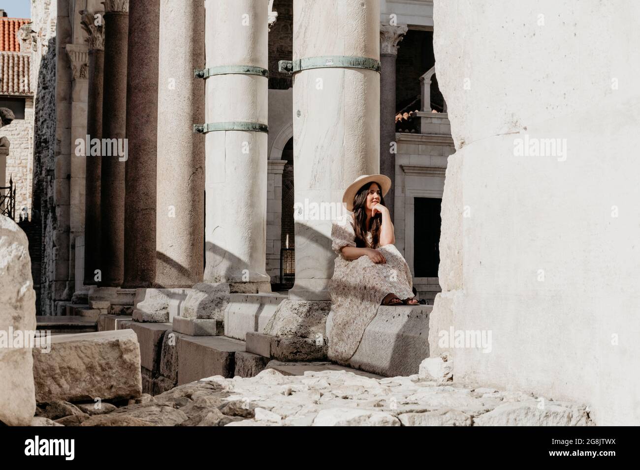 Beautiful young woman sitting on stone of ancient monument in Split ...