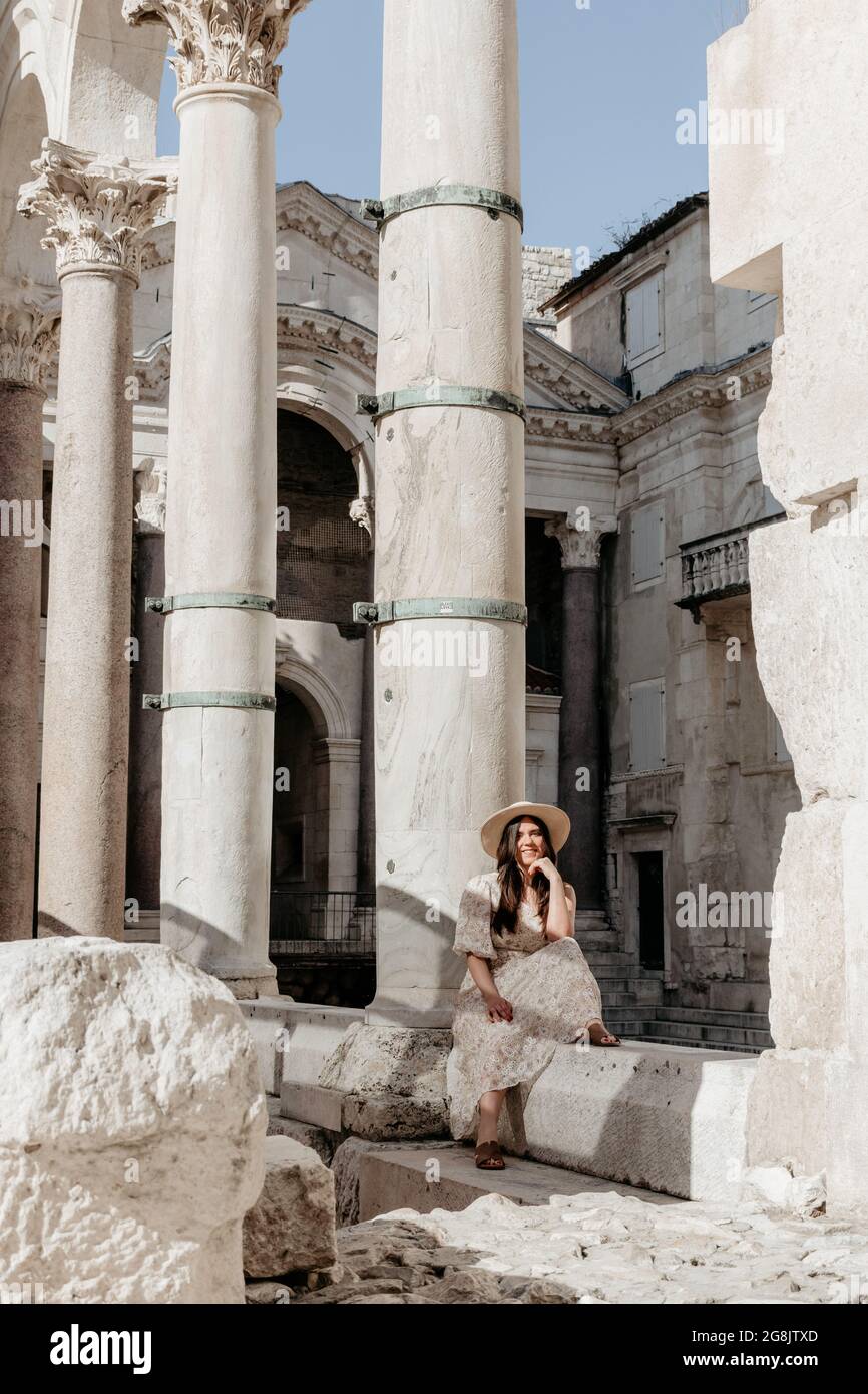 Beautiful young woman sitting on stone of ancient monument in Split ...