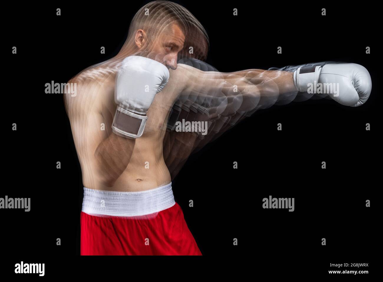 One young professional male boxer in red shorts and gloves training ...