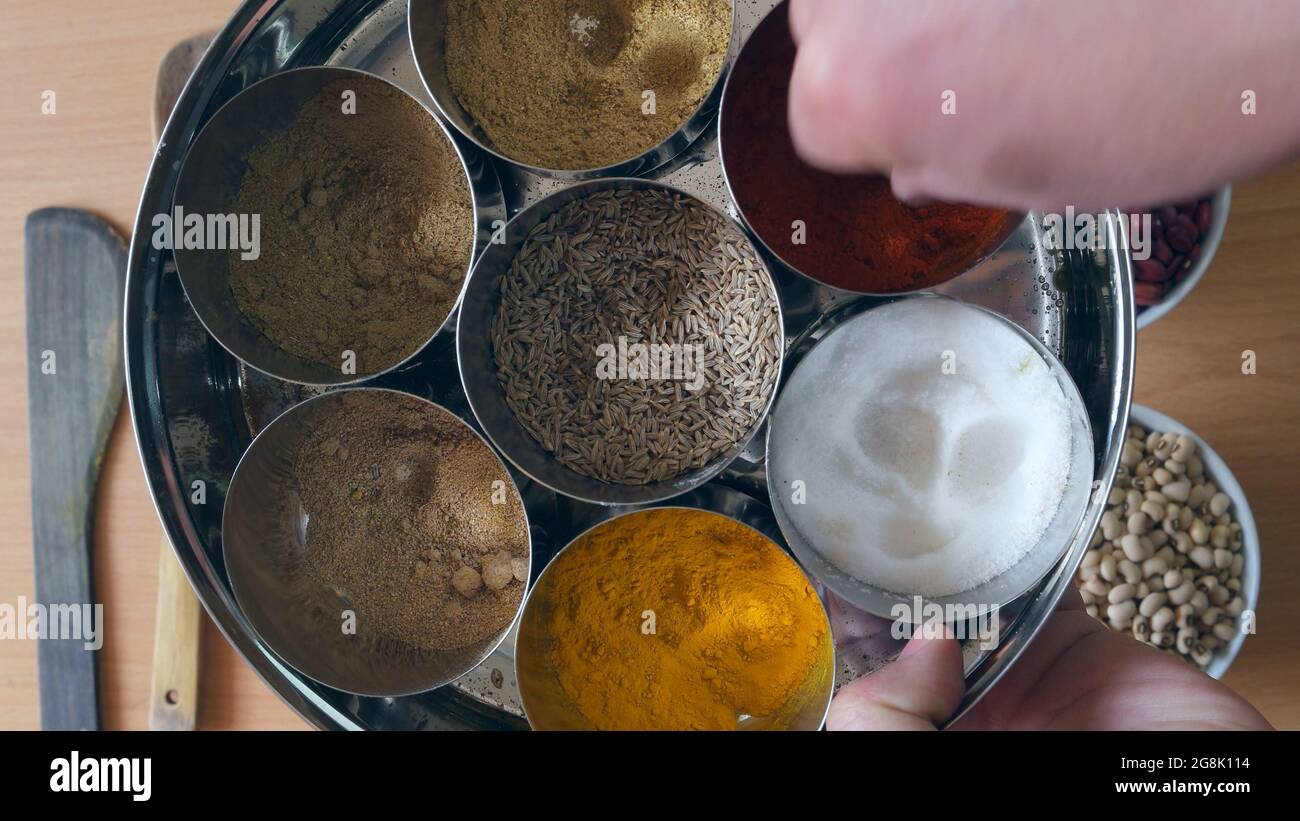 Top view of small metal jars filled with various Indian spices and ...