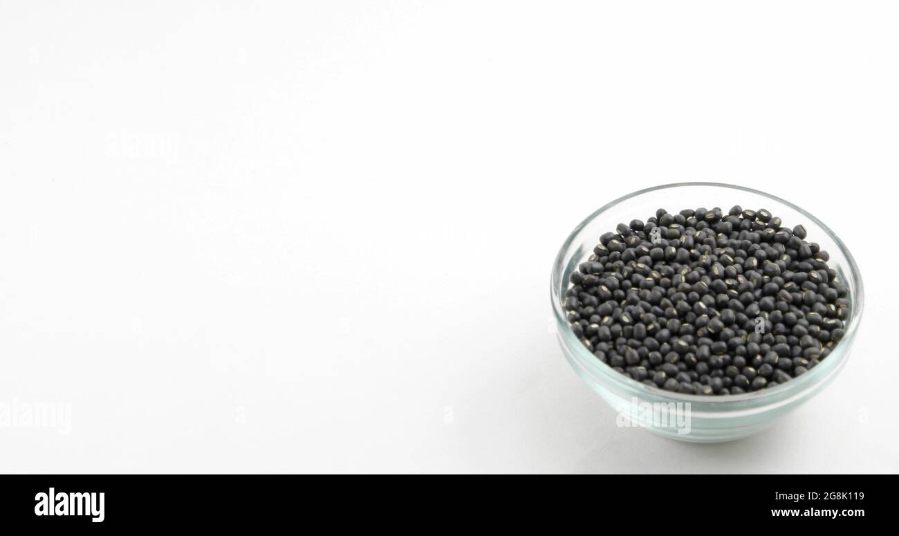 Closeup of black mung beans in a small glass bowl on a white background ...