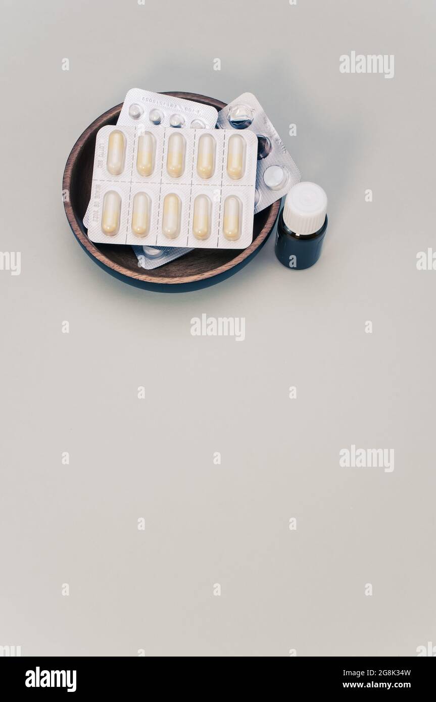 Small bowl full of pill blister packs and a vial isolated on a beige ...