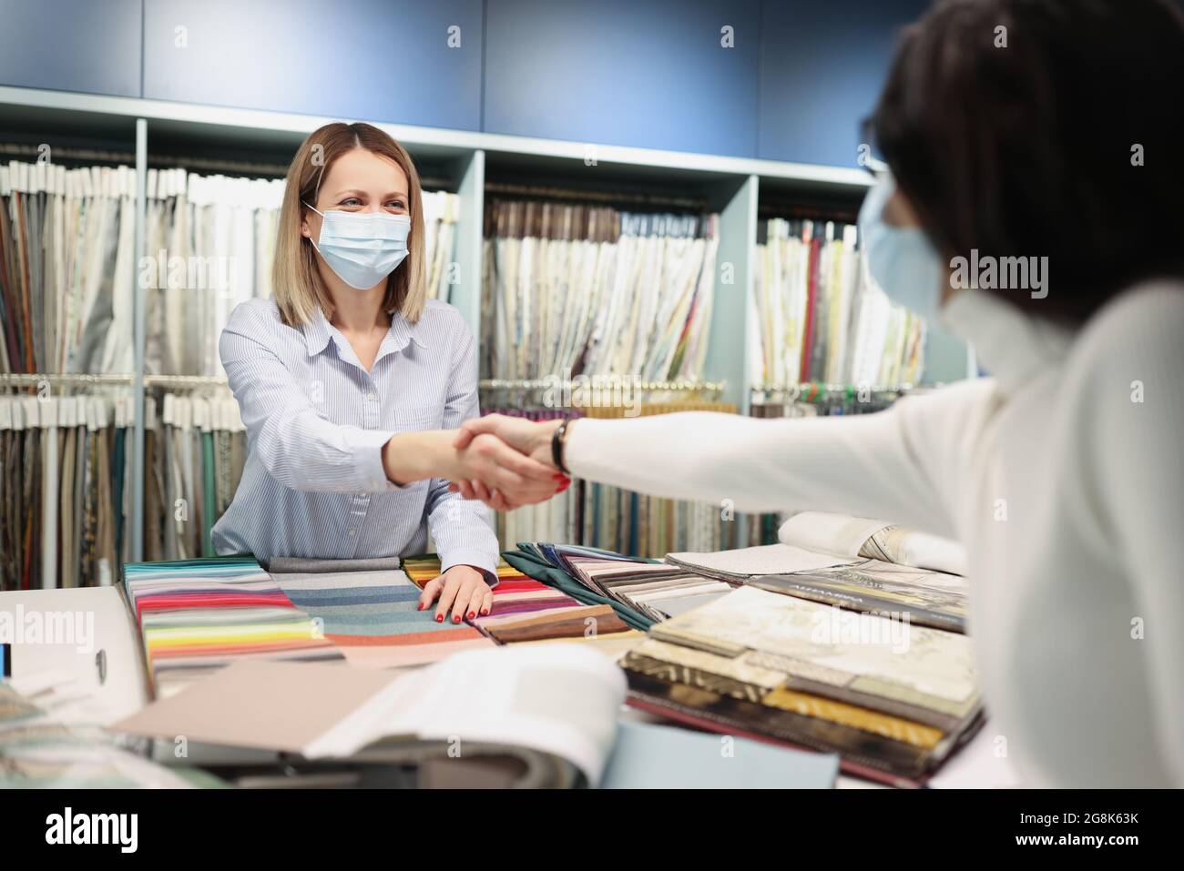Buyer and seller in protective medical masks shake hands in tissue ...