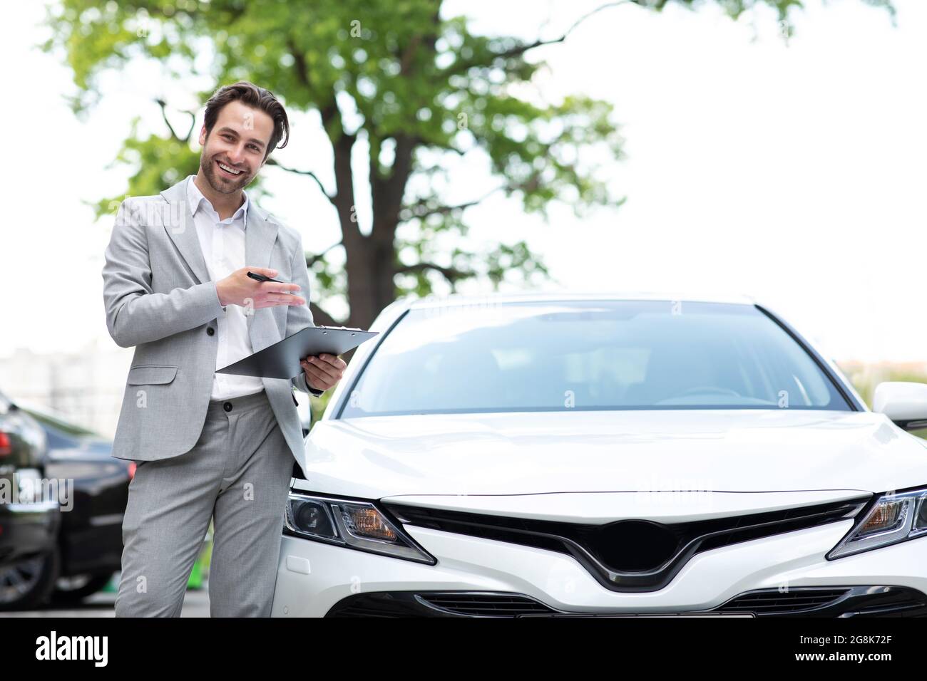 Handsome car dealership worker in suit, holding folder and smiling ...