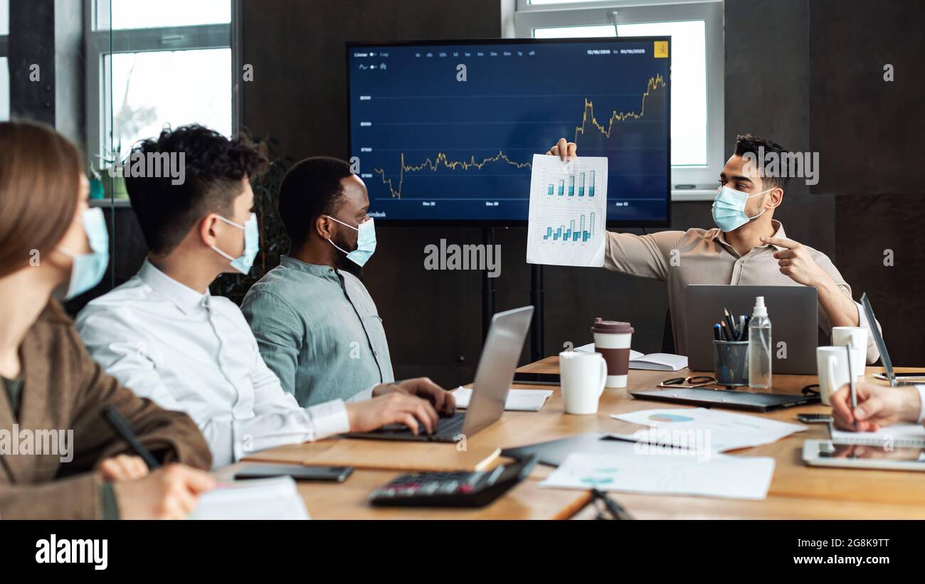 Man in protective medical mask showing paper with graph diagram Stock ...