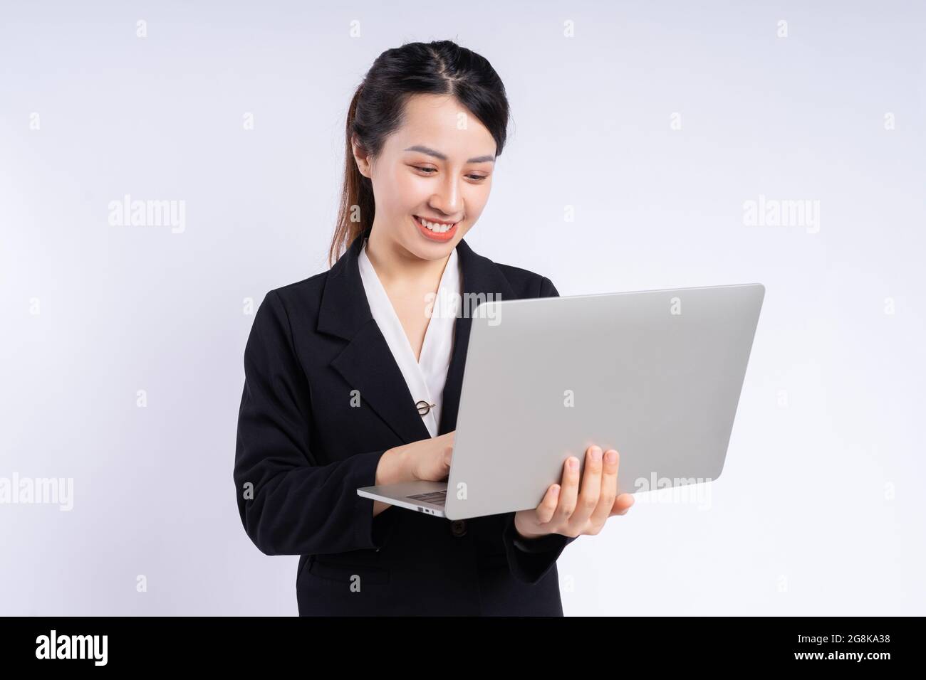 Young Vietnamese female employee in black suit happily using a laptop ...