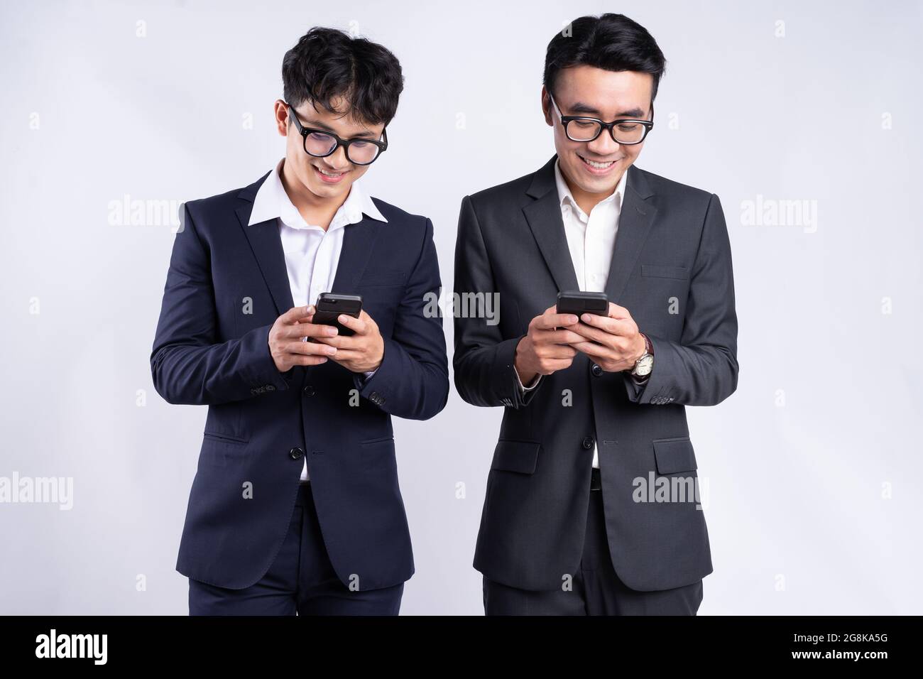 Young Vietnamese male employees in suits smiling and using phones Stock ...