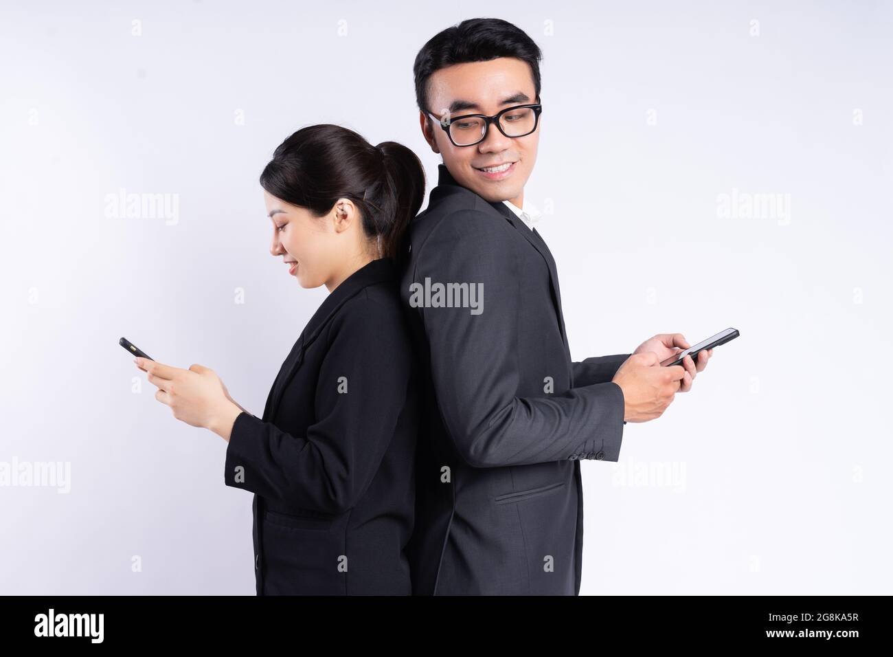 Young Vietnamese employees in suits standing back to back and sending ...