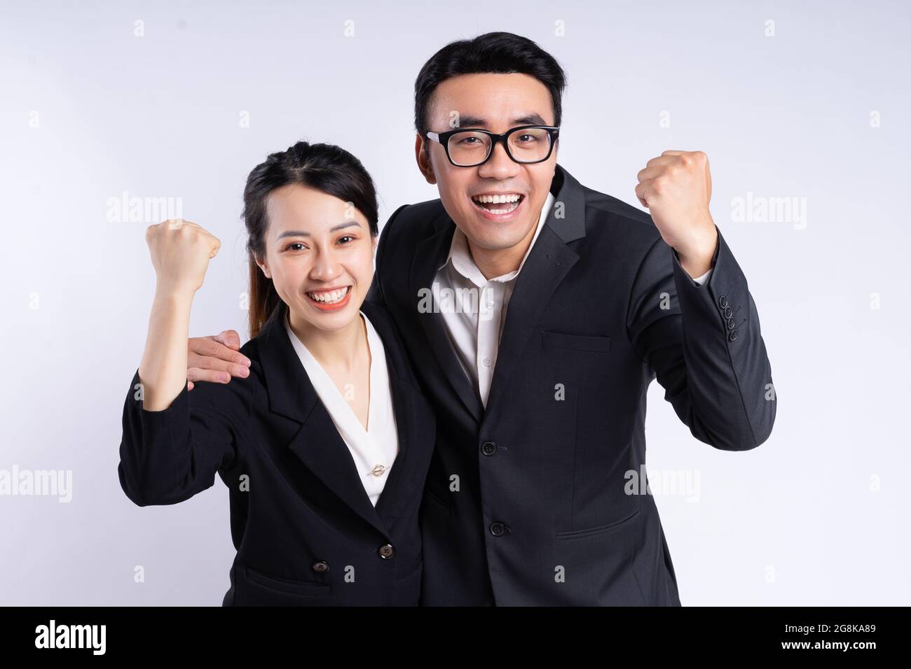 Young Vietnamese employees in suits with raised fists on background of ...