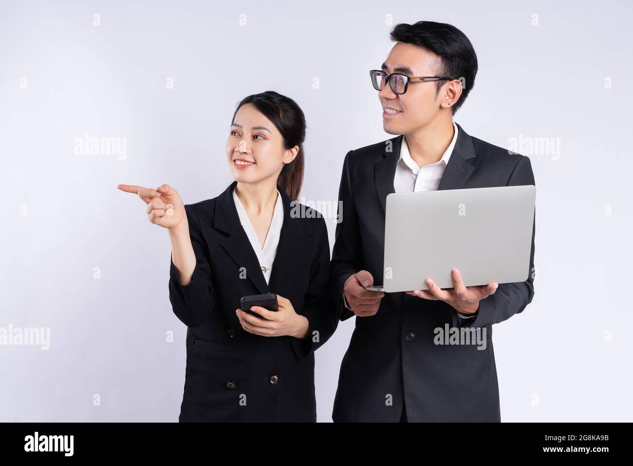 Young Vietnamese employees in suits pointing aside at the empty space ...