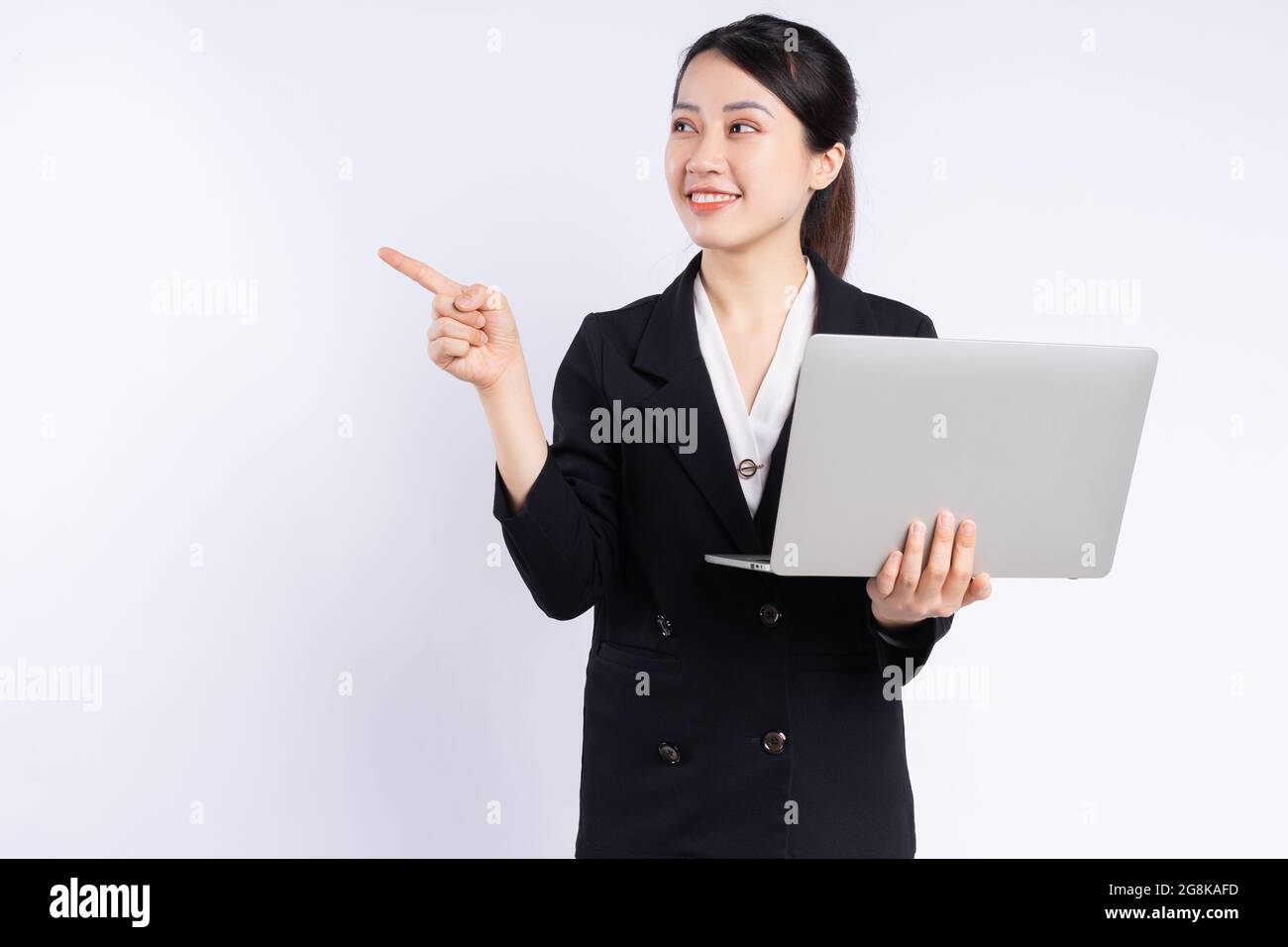 Young Vietnamese female employee in black suit holding a laptop and ...