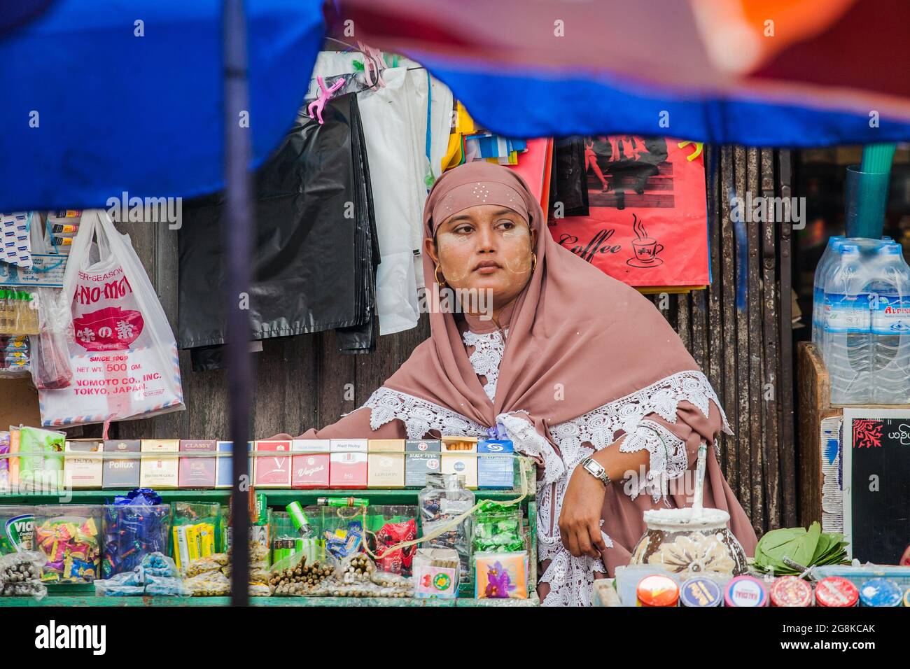 Female Muslim stall trader wearing hijab headdress and thanaka in ...