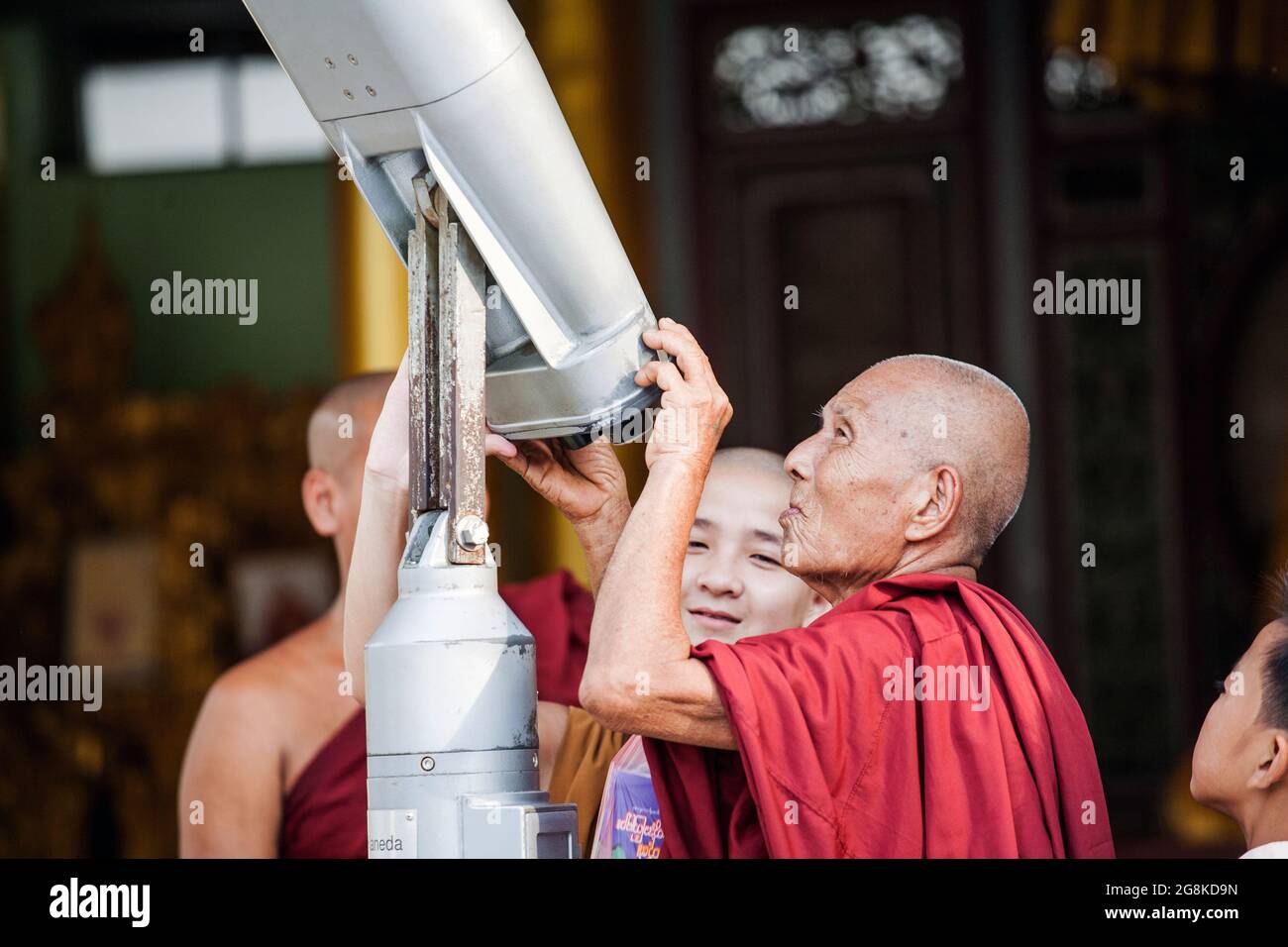 Group of Burmese Buddhist monks wearing maroon robes look through ...