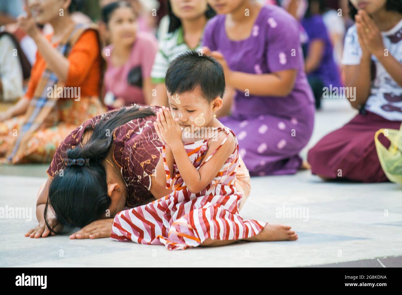 Cute young Burmese girl sits praying with thanaka face powder at ...
