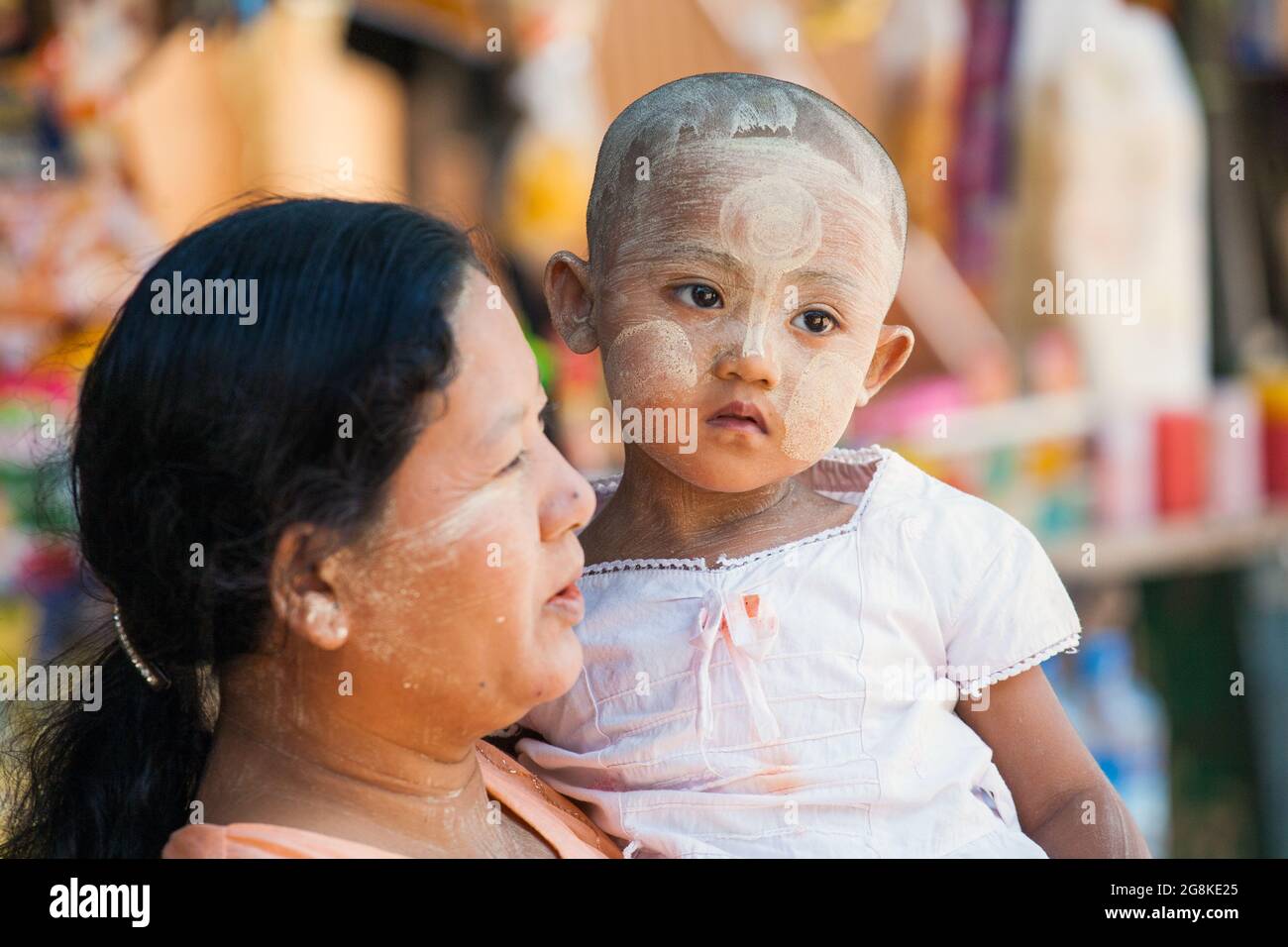 Young Burmese girl with shaved head and face full of thanaka patterns ...