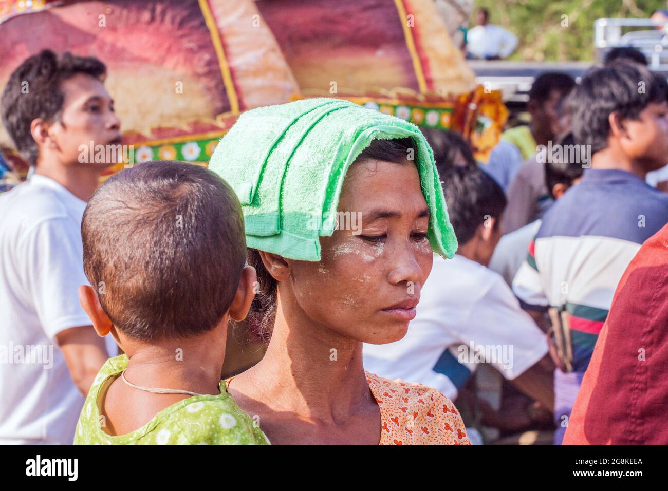 Pretty attractive mother with thanaka face powder carries young child ...