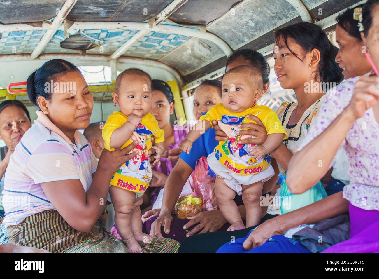 Burmese females holding up new born twin babies in busy local bus ...