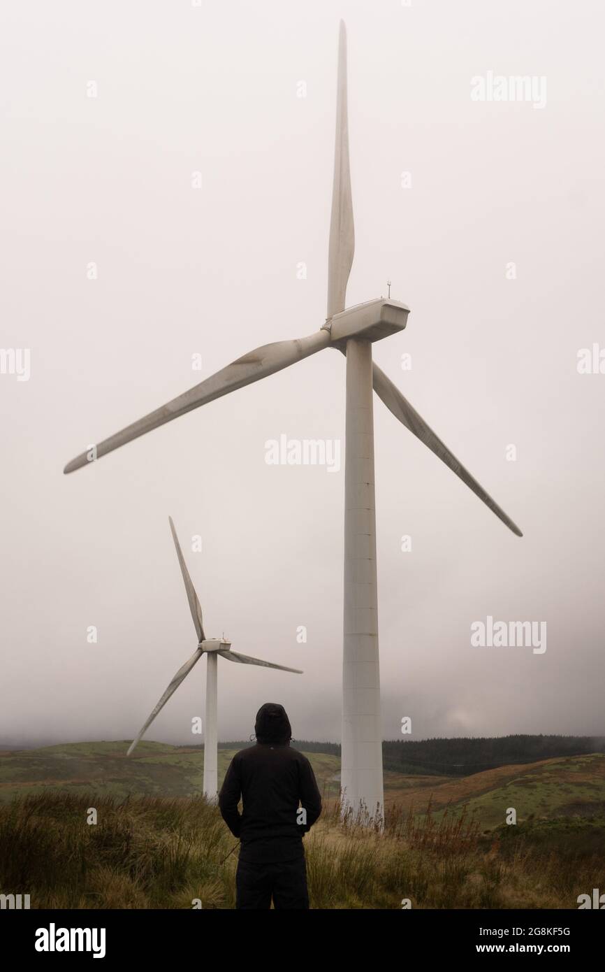 A mysterious hooded figure. Looking up at wind turbines on a mountain ...
